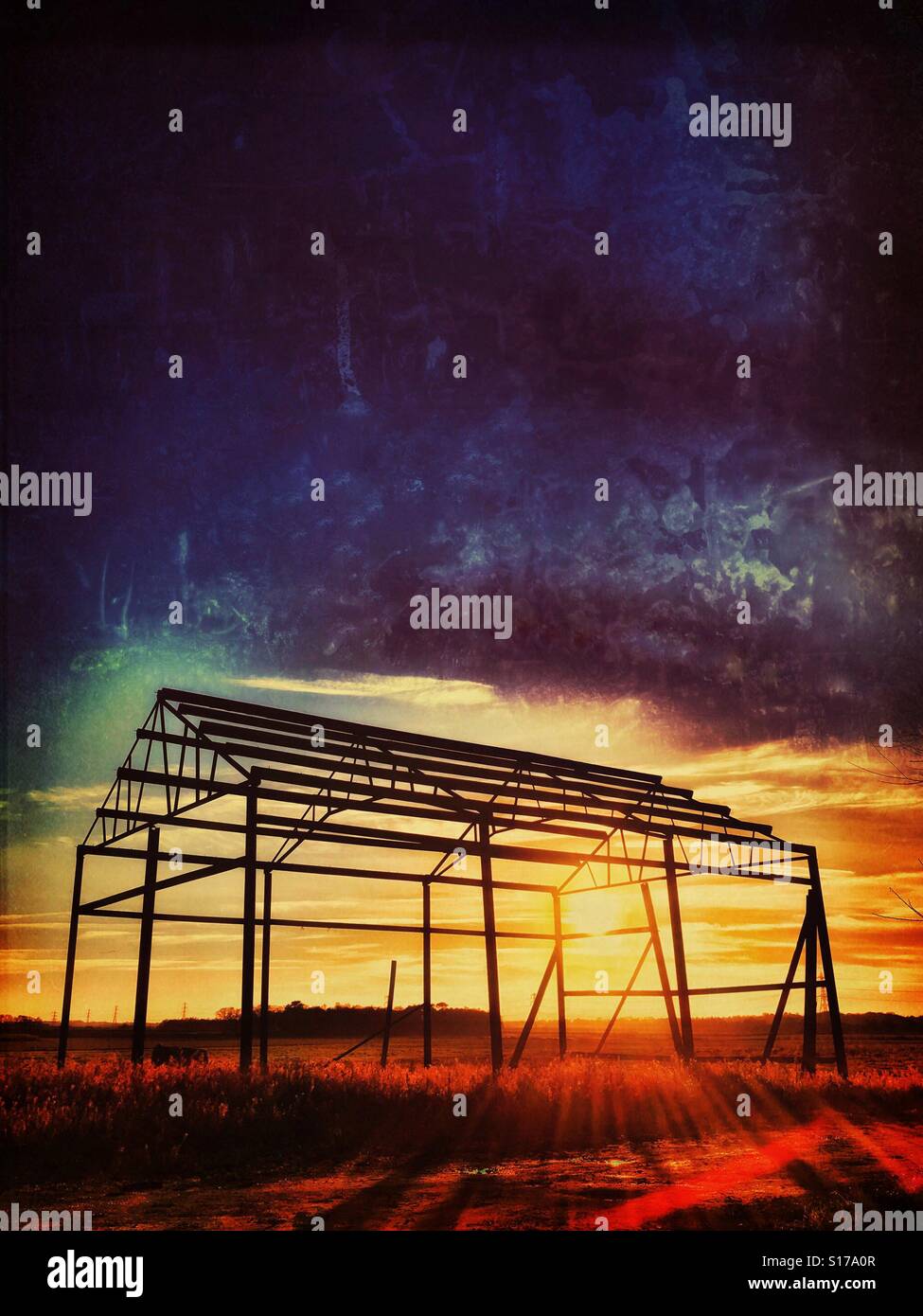 Skeleton structure of derelict barn silhouetted against late afternoon ...