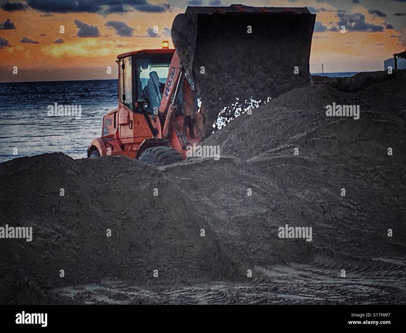 Bulldozer on beach at sunset Stock Photo - Alamy