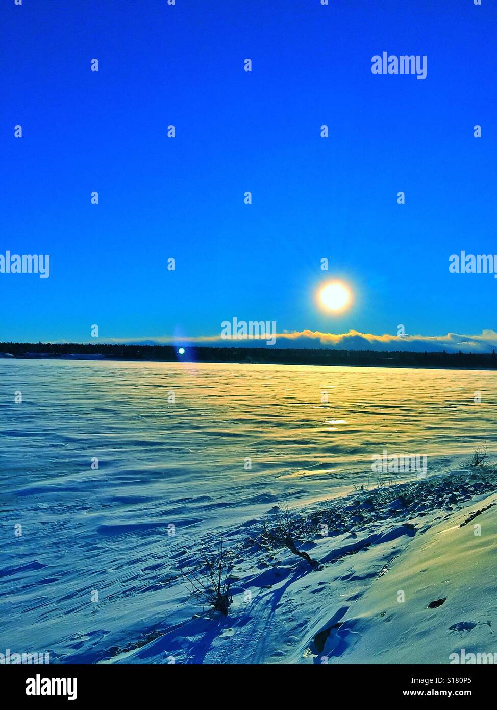 Frozen lake at sunset with lens flare Stock Photo - Alamy