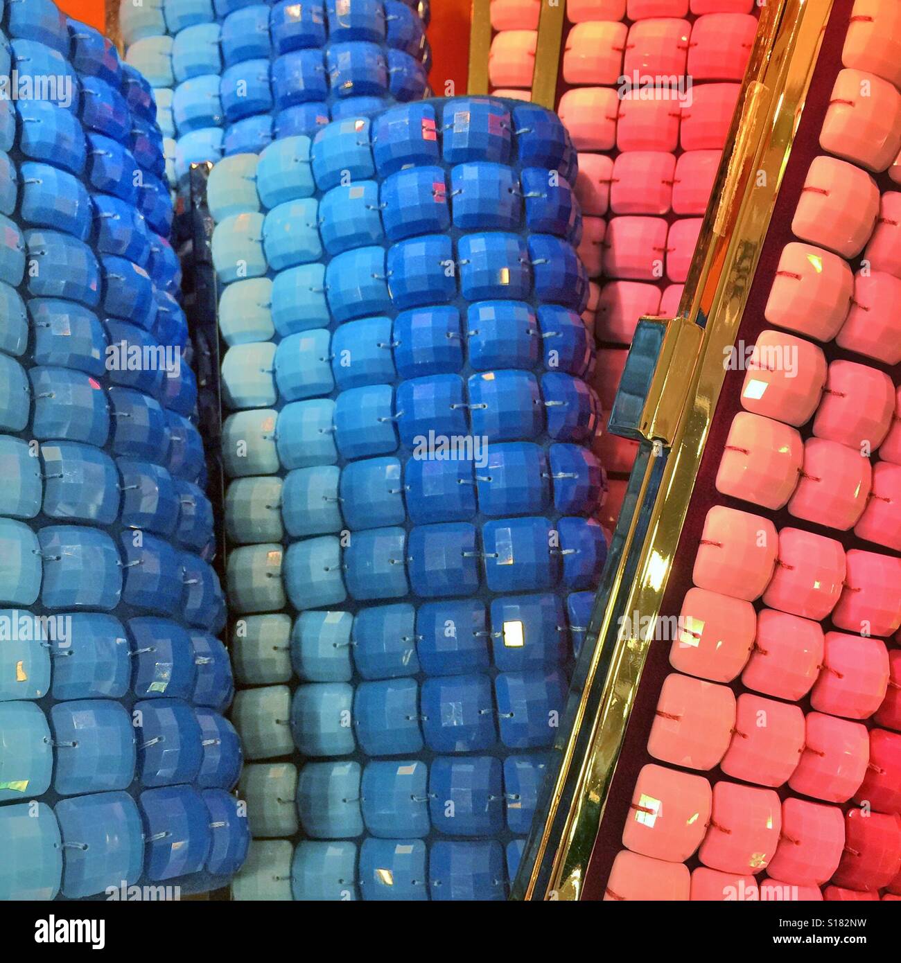 Brightly colored pink and blue handbags made from many plastic squares ...