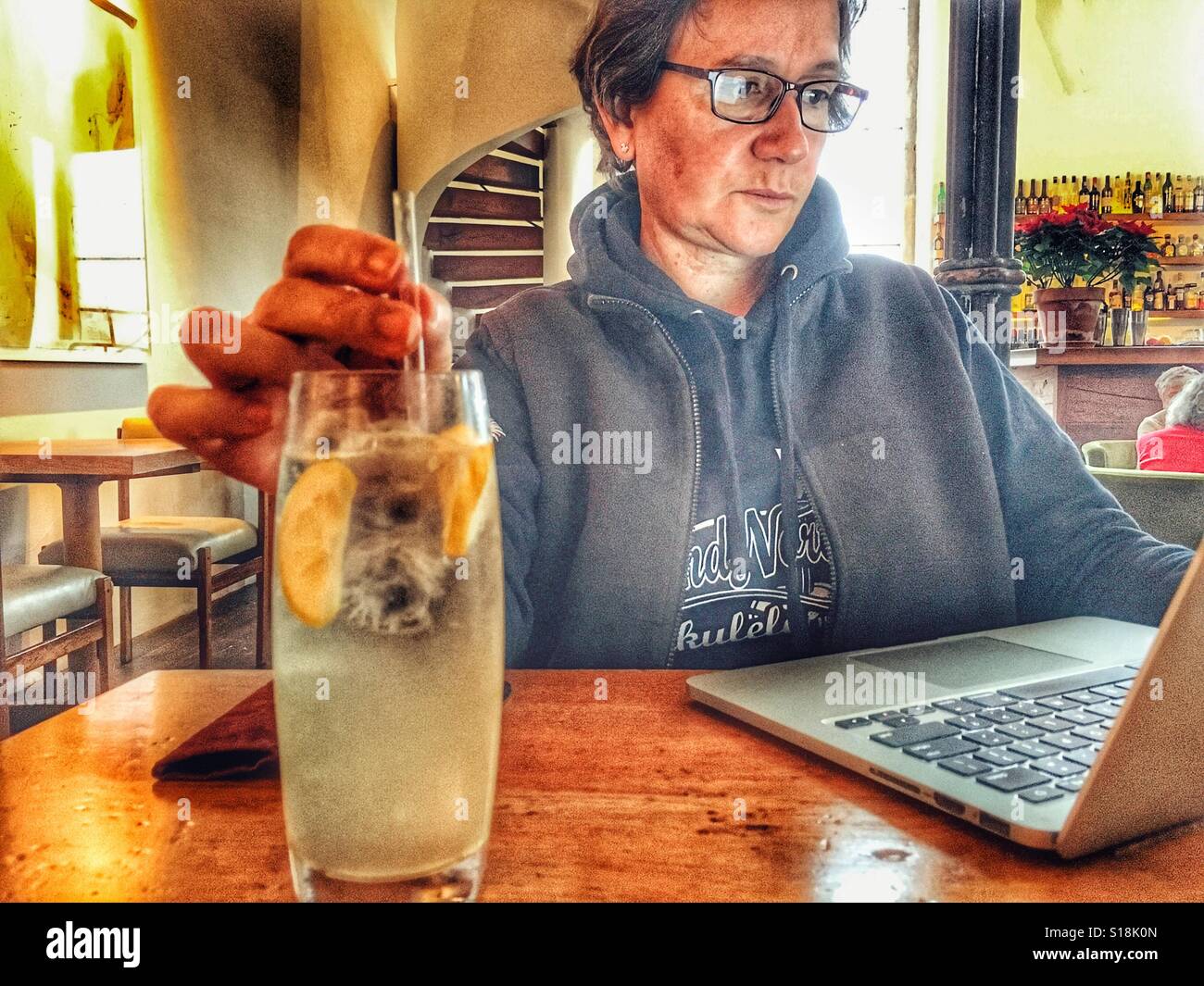 Woman in a restaurant, working on her laptop computer and drinking ...