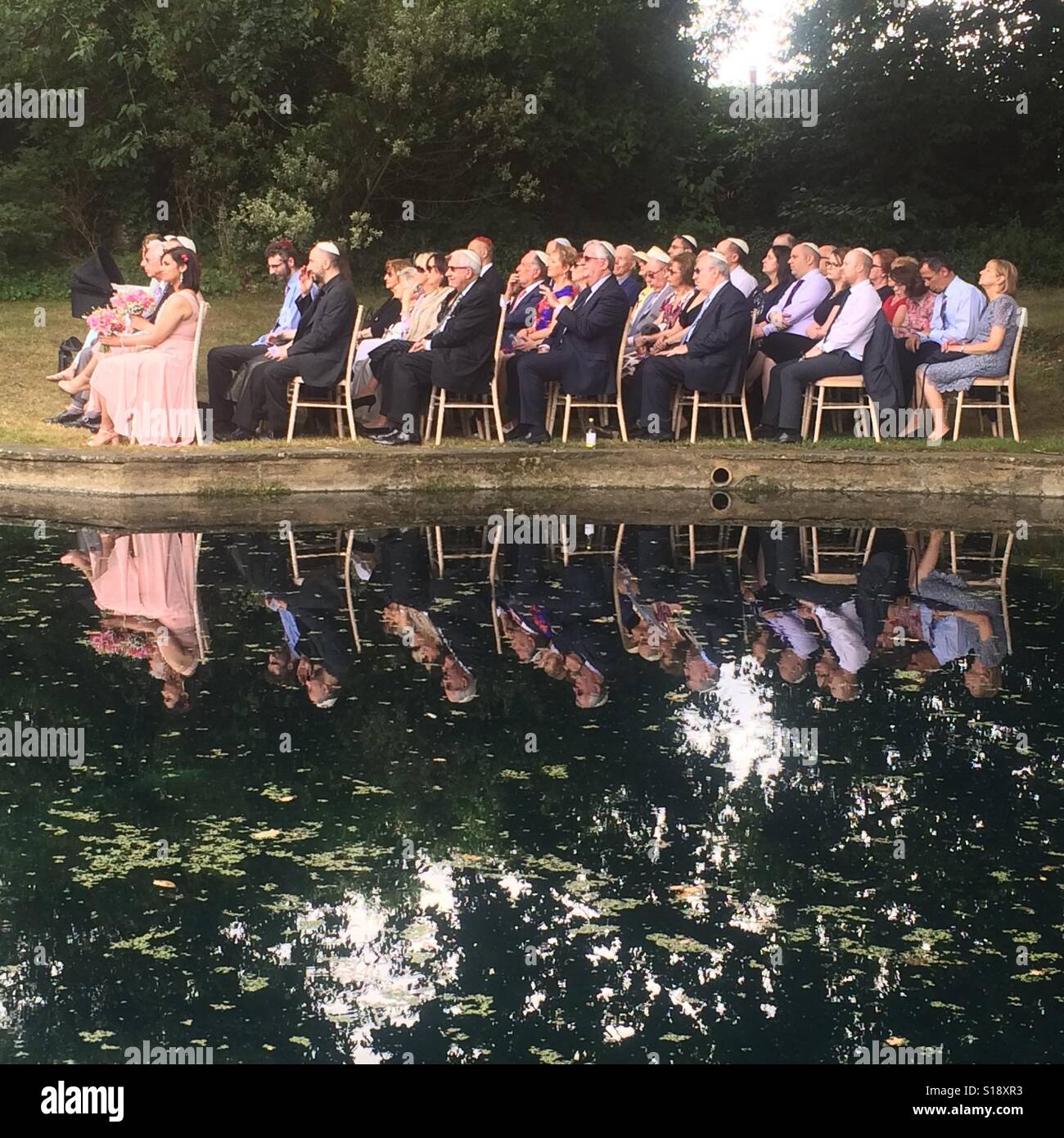 Wedding congregation seated by water creating a reflection Stock Photo ...