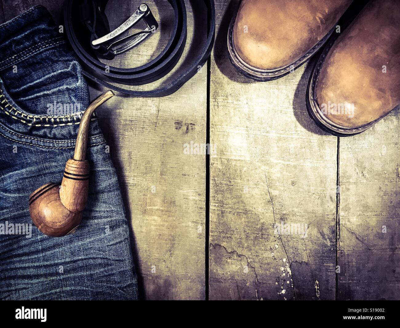 Wooden smoking pipe, leather boots and blue jeans on the wooden ...
