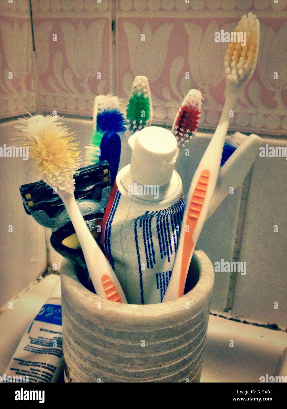 Toothbrushes and toothpaste in a beaker in the bathroom Stock Photo - Alamy
