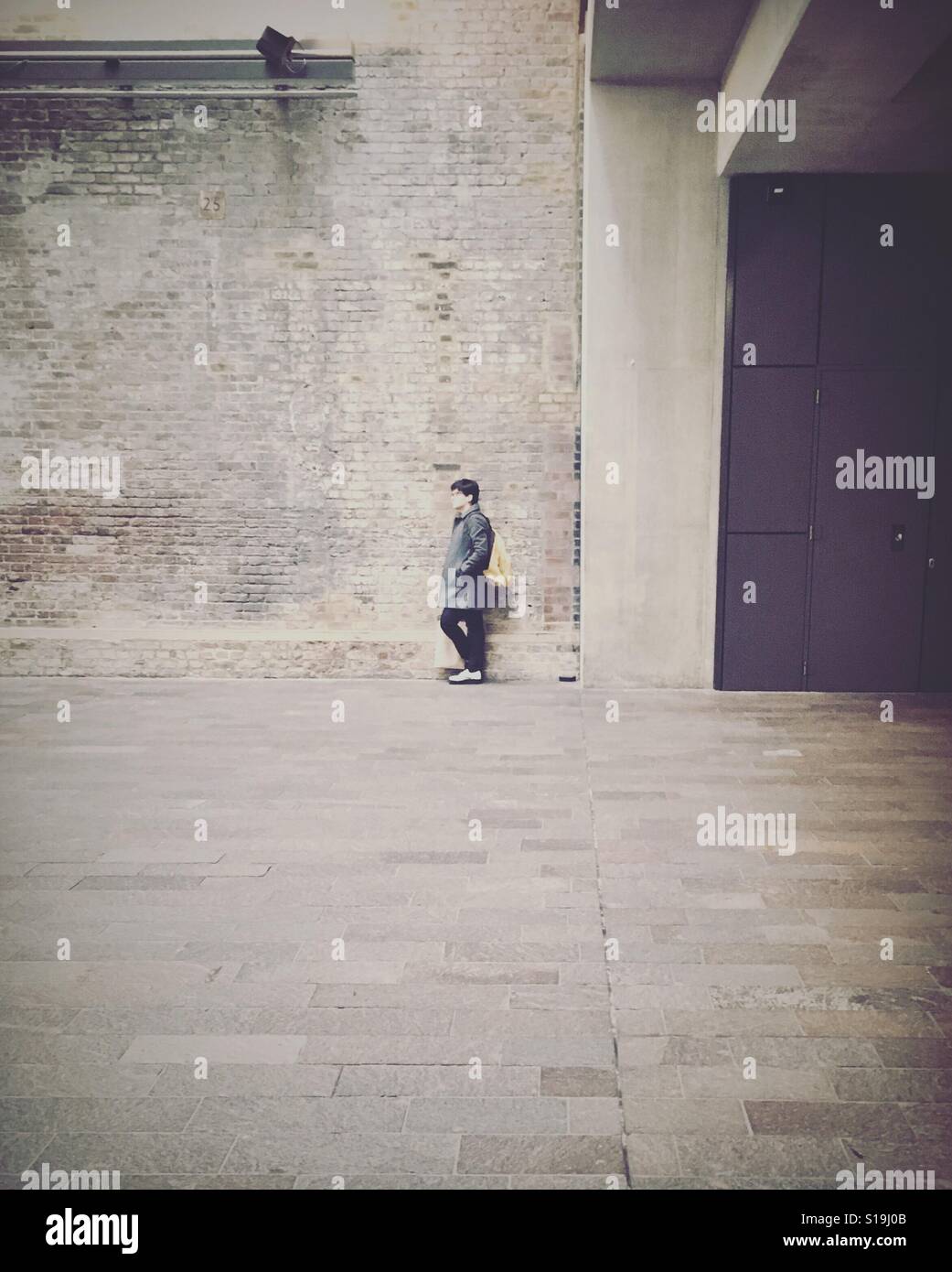 Person standing against a wall Stock Photo - Alamy