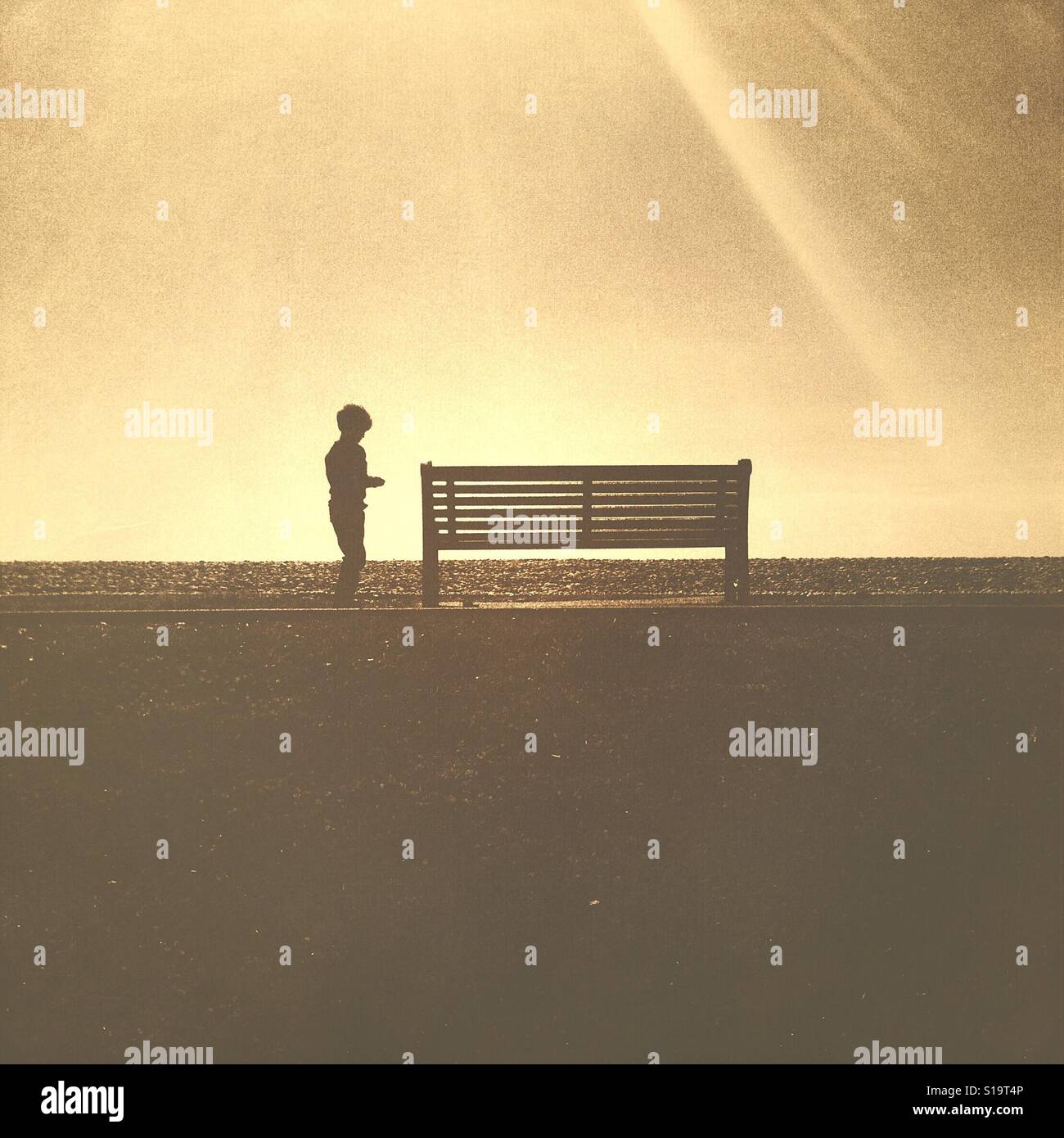 Boy bench beach sunset Stock Photo - Alamy