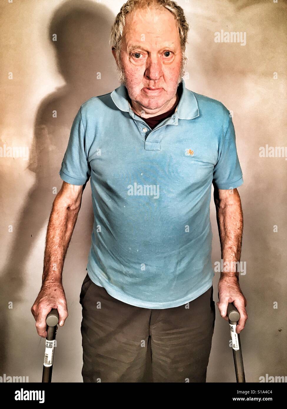 Elderly man using walking sticks Stock Photo - Alamy