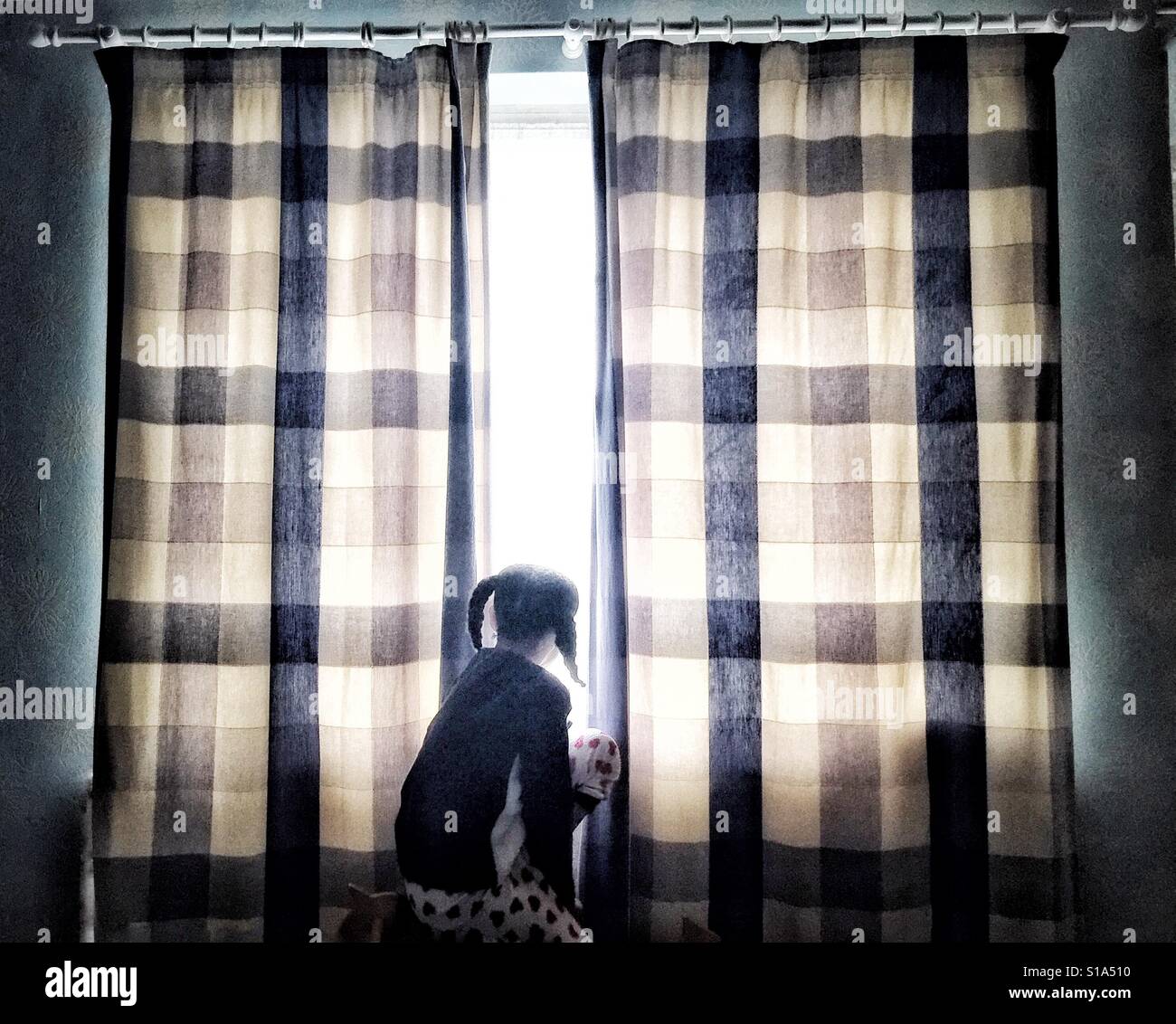 A young girl looks out of the window Stock Photo - Alamy