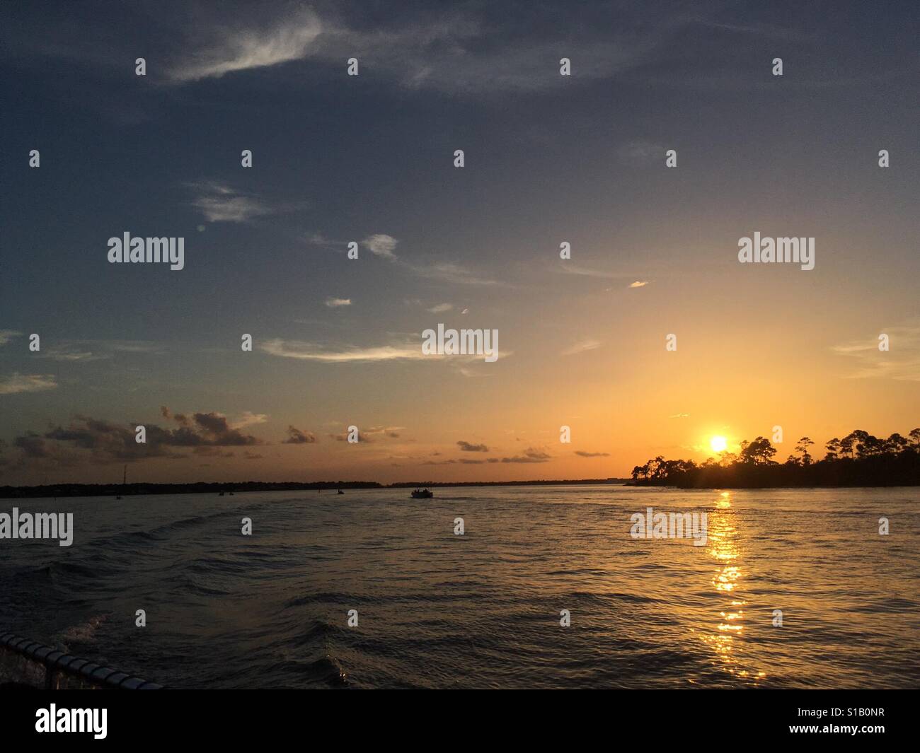 Ocean sunset. Boating. Offshore. Trees on the Horizon Stock Photo - Alamy