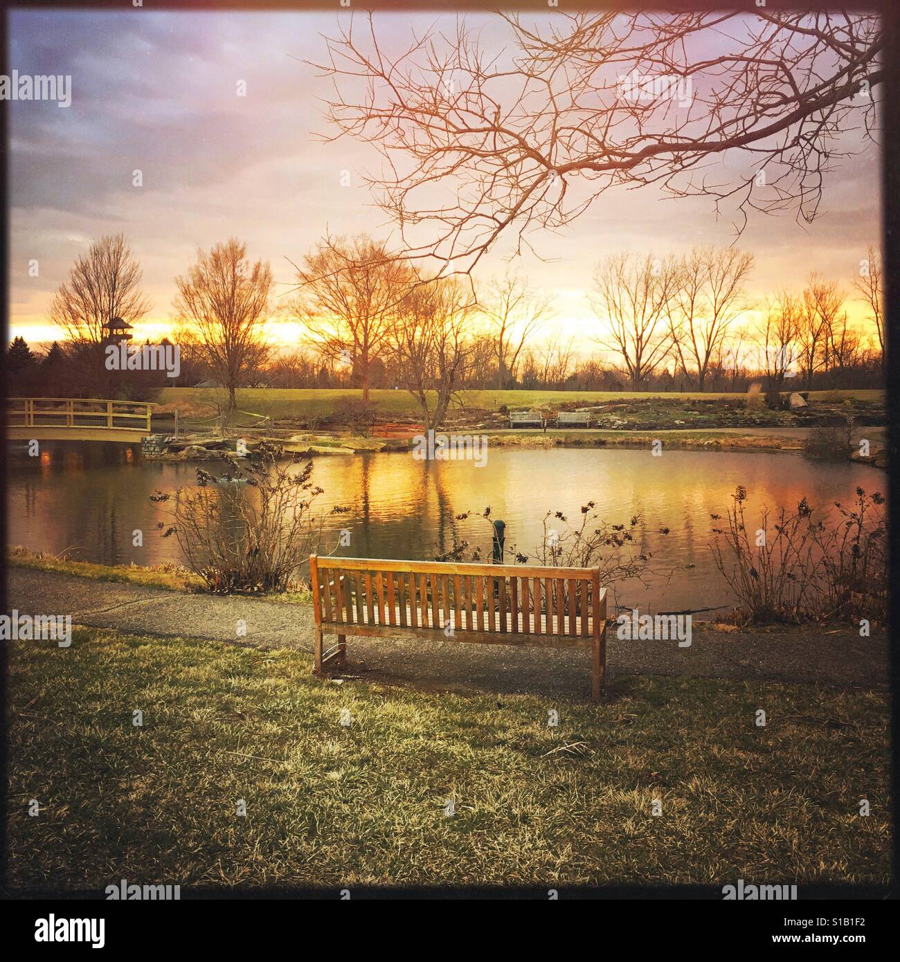 A park bench, by the lake, is facing the beautiful sunset (1 Stock ...