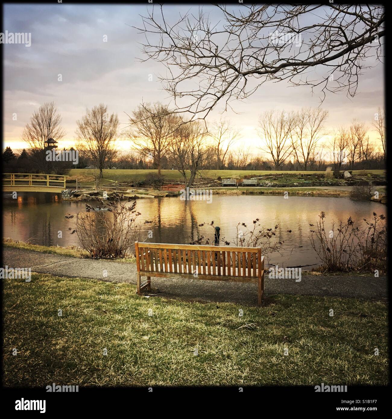 A park bench, by the lake, is facing the beautiful sunset (2 Stock ...