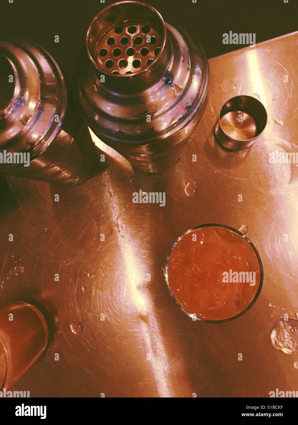 Top down view of wet cocktail shakers and orange mixed drinks on ...