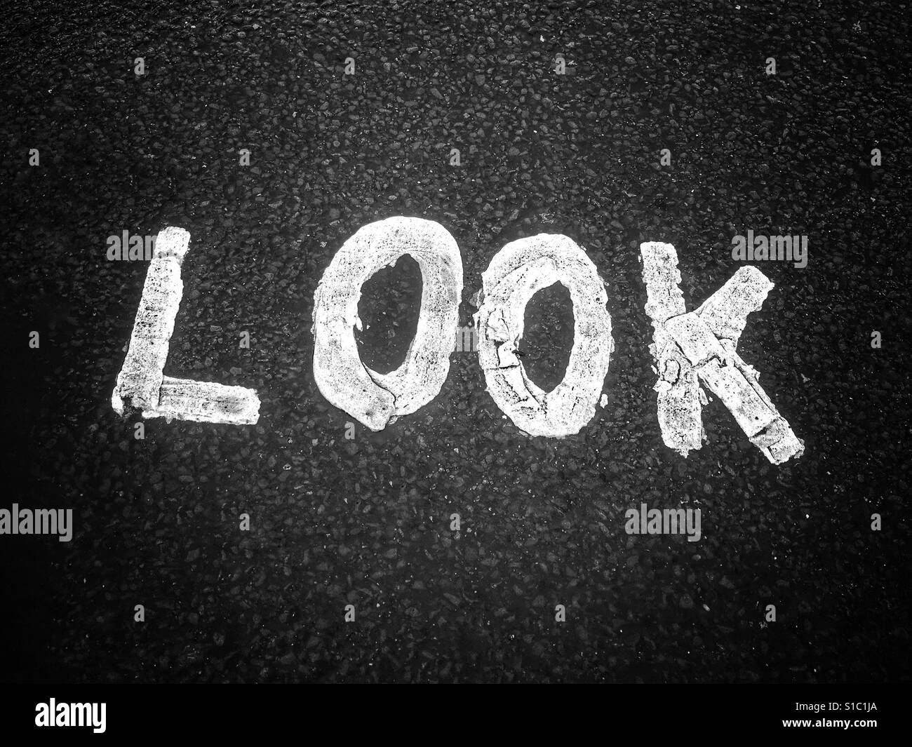 White painted road marking sign depicting the word Look Stock Photo - Alamy