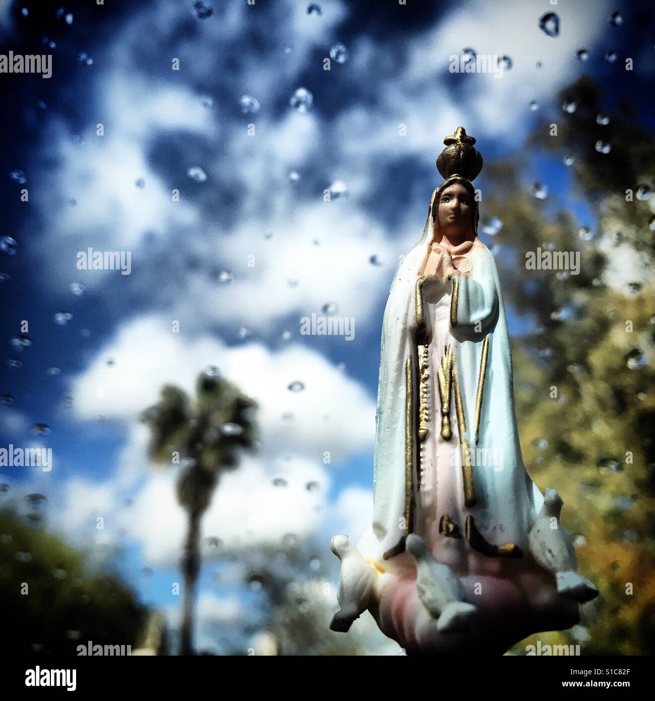 A miniature of Our Lady of Fatima in front of a glass window covered ...