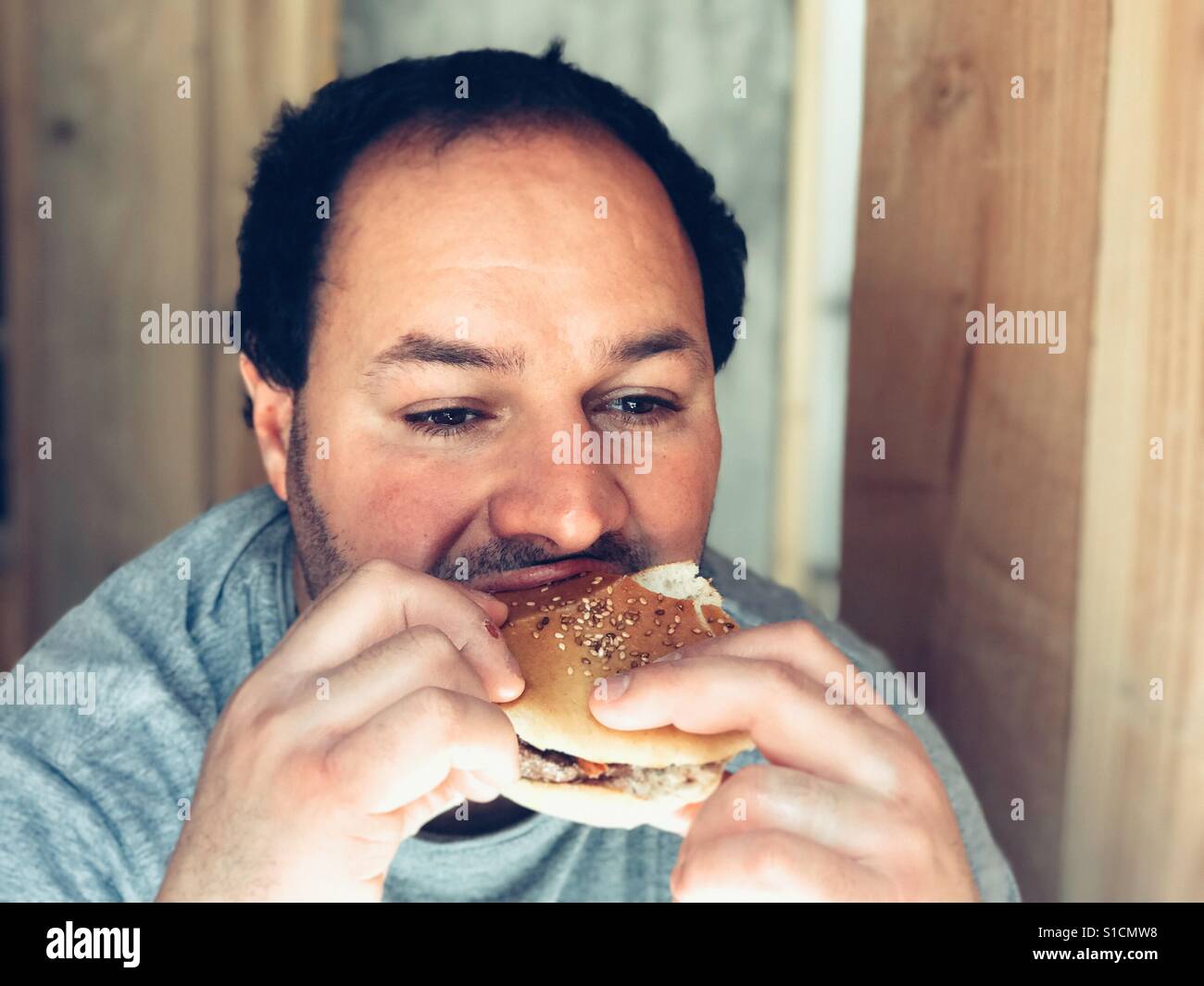 Unhappy man eating a burger Stock Photo - Alamy