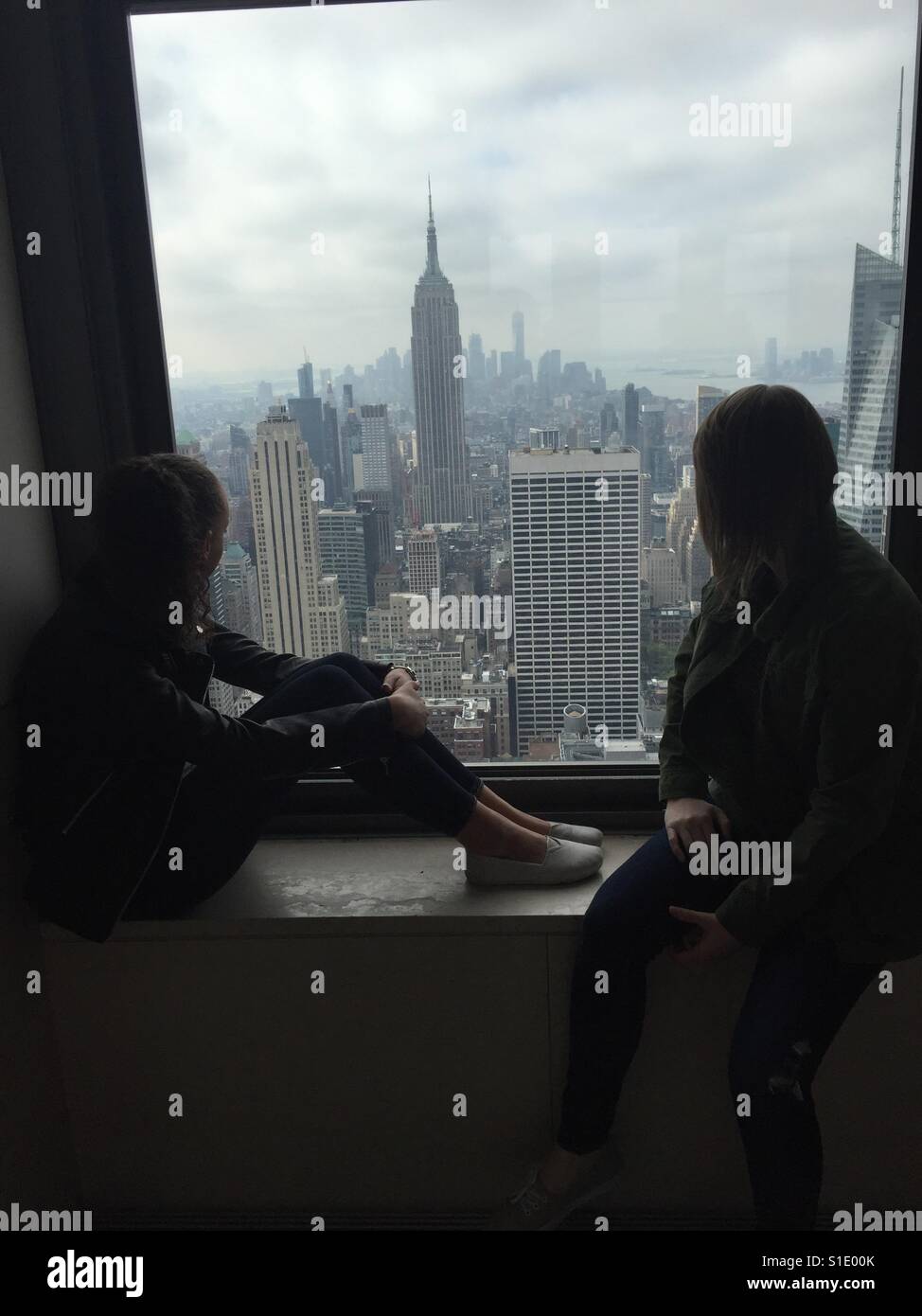 2 girls looking over the views of New York out a giant window Stock ...