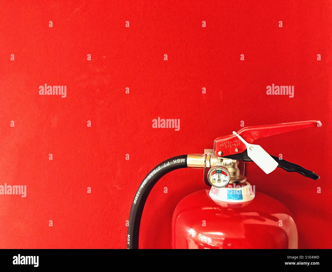 Fire extinguisher detail against a red background Stock Photo - Alamy