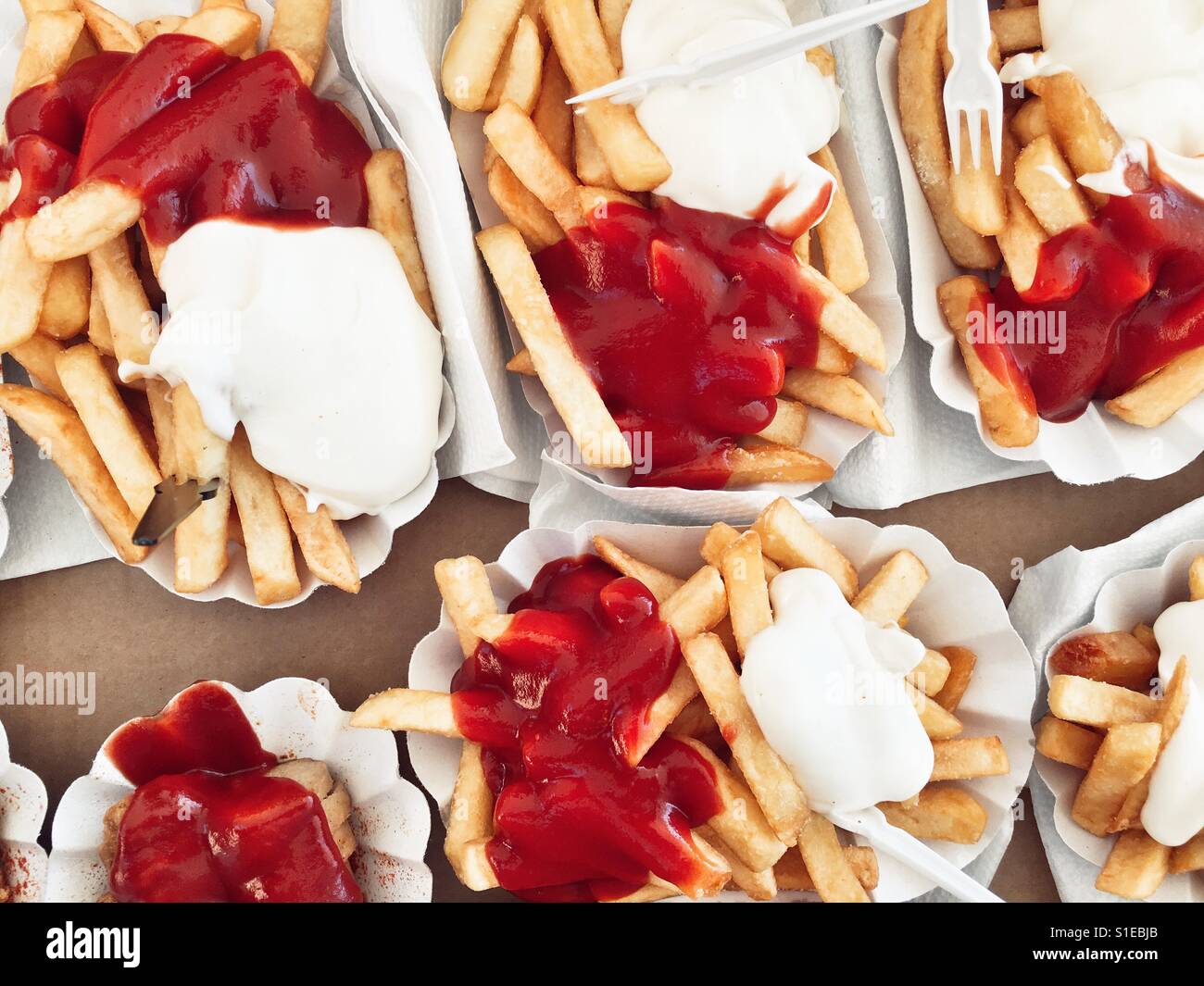 Paper plates of fries with ketchup and mayonnaise and curry sausage ...