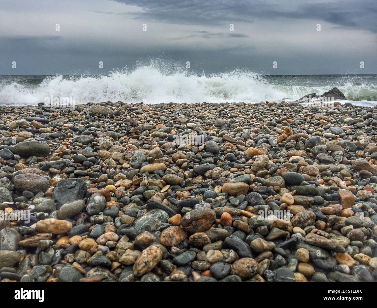 Breaking wave on shingle beach Stock Photo - Alamy