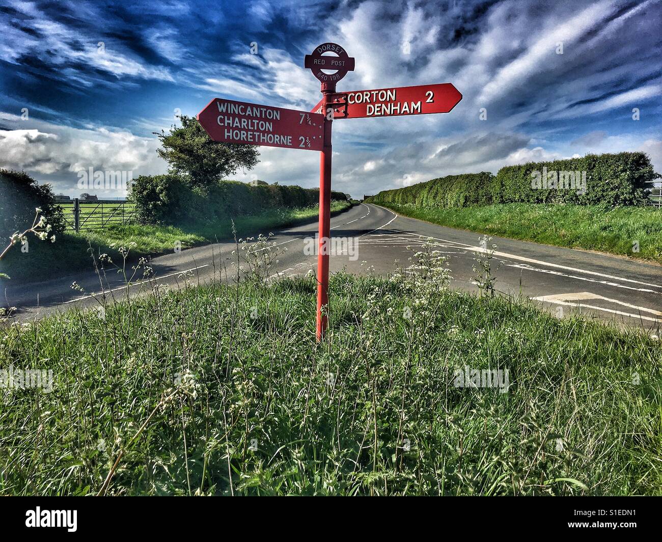 Summer landscape with a Dorset red sign post and country lane junction ...