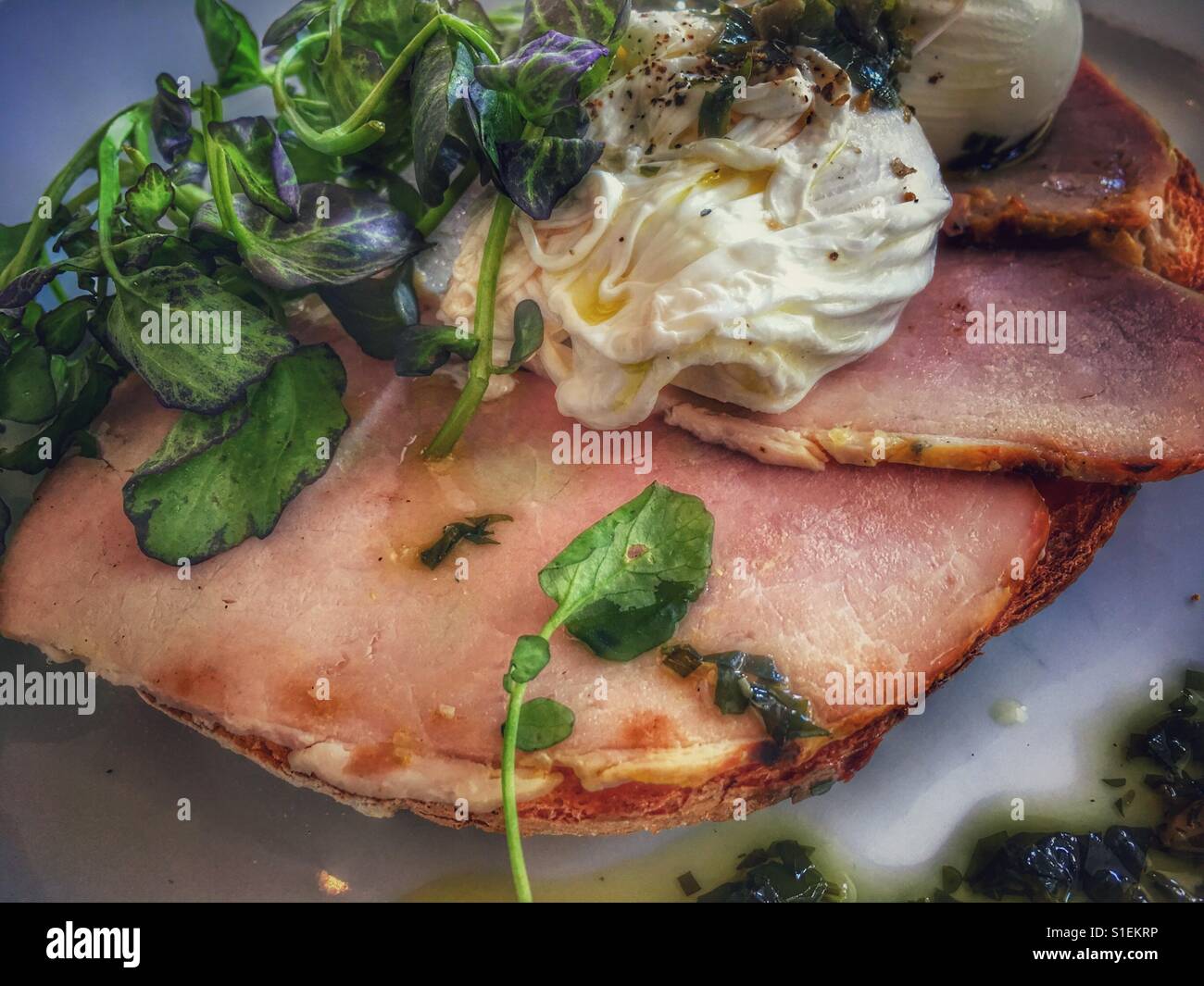 Baked ham, poached eggs and pea shoots on toast Stock Photo - Alamy