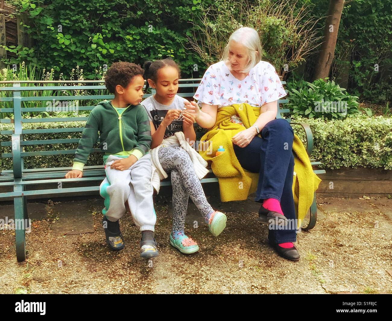 A family sitting on a park bench Stock Photo - Alamy