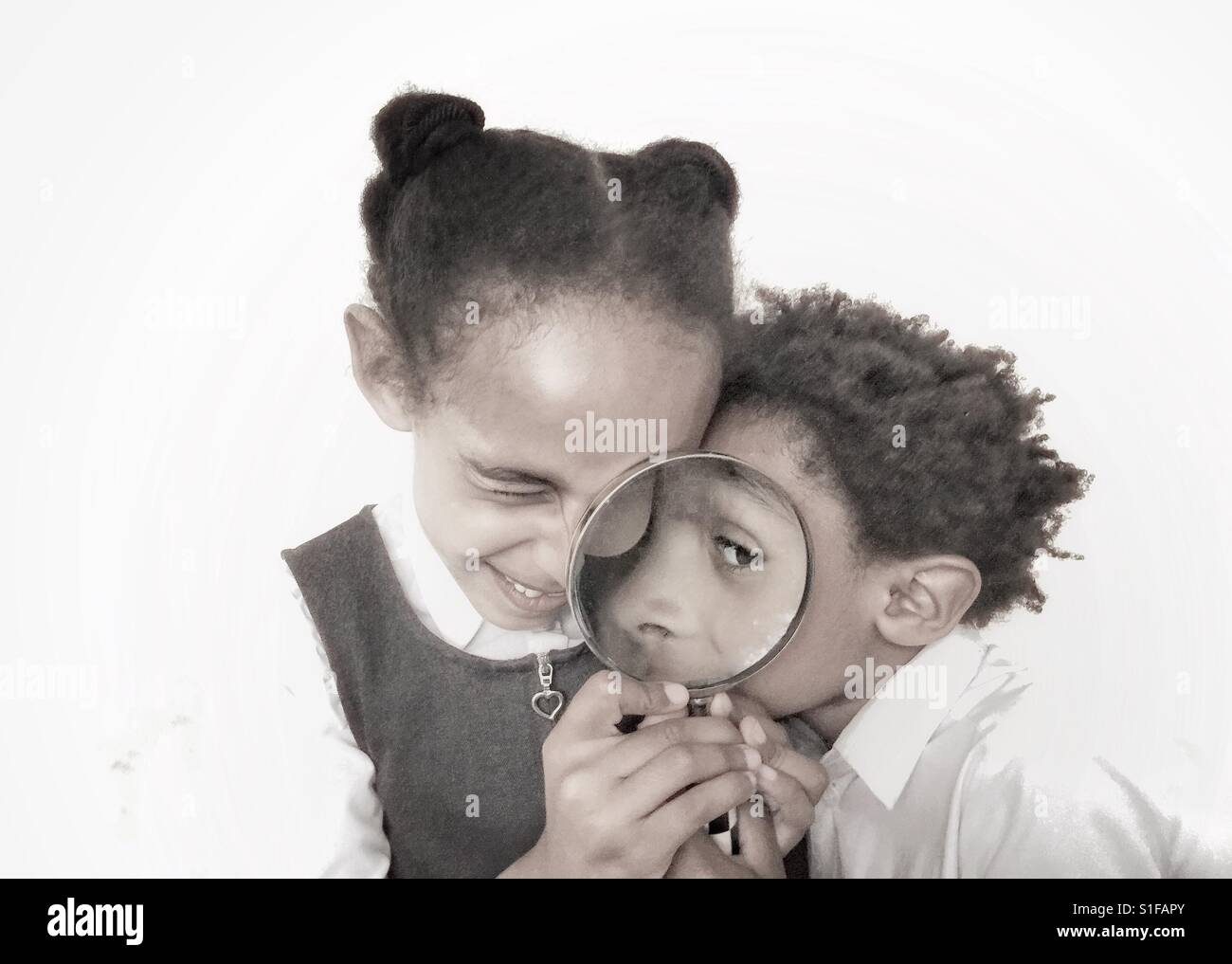 Kids looking through a magnifying glass Stock Photo - Alamy