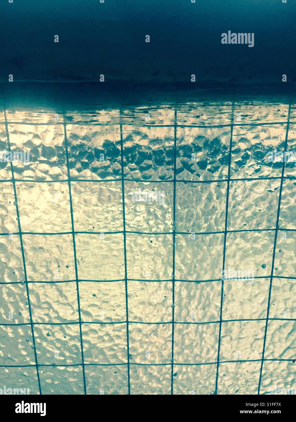 Window with bubble glass and wire squared sections and light coming ...