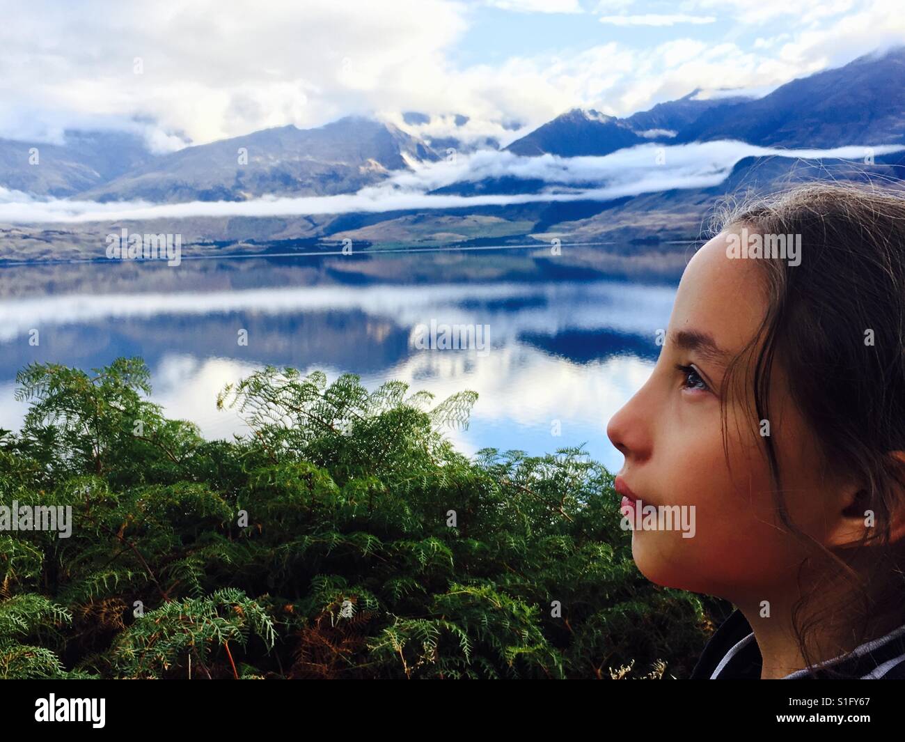 Little girl looking up at the sky with scenery in the background Stock ...
