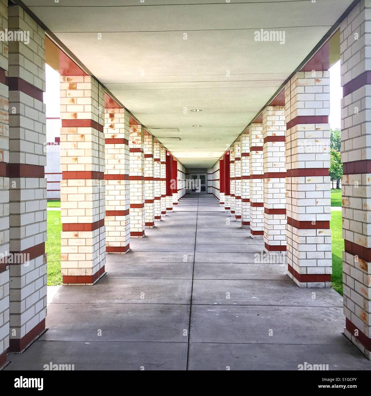 A long walkway flanked by pillars leading to a doorway Stock Photo - Alamy
