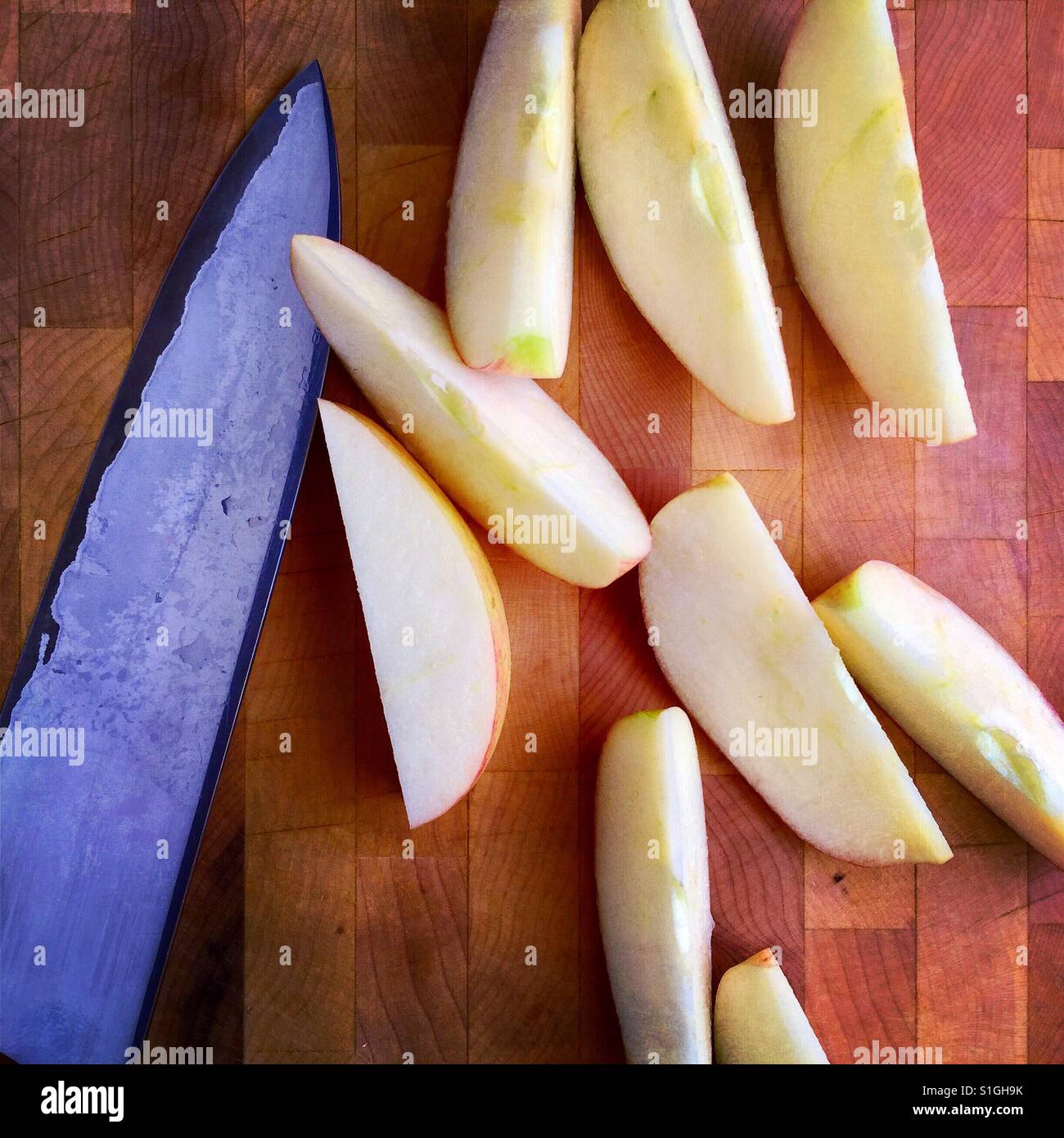A knife and freshly cut apple slices on a wood cutting board Stock ...