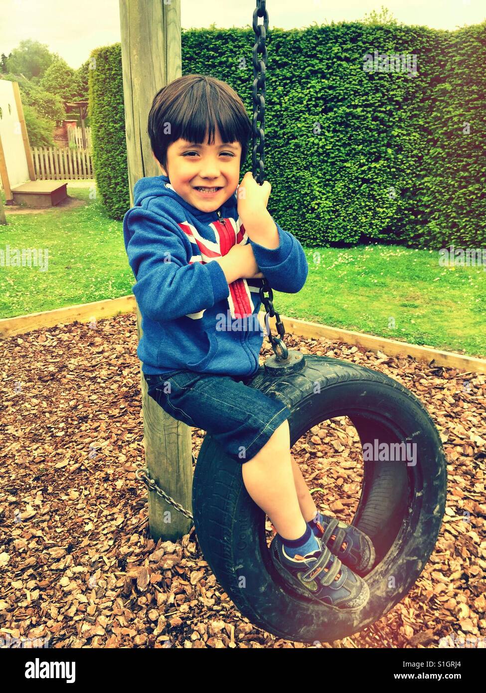 A young boy swinging from a tyre Stock Photo - Alamy