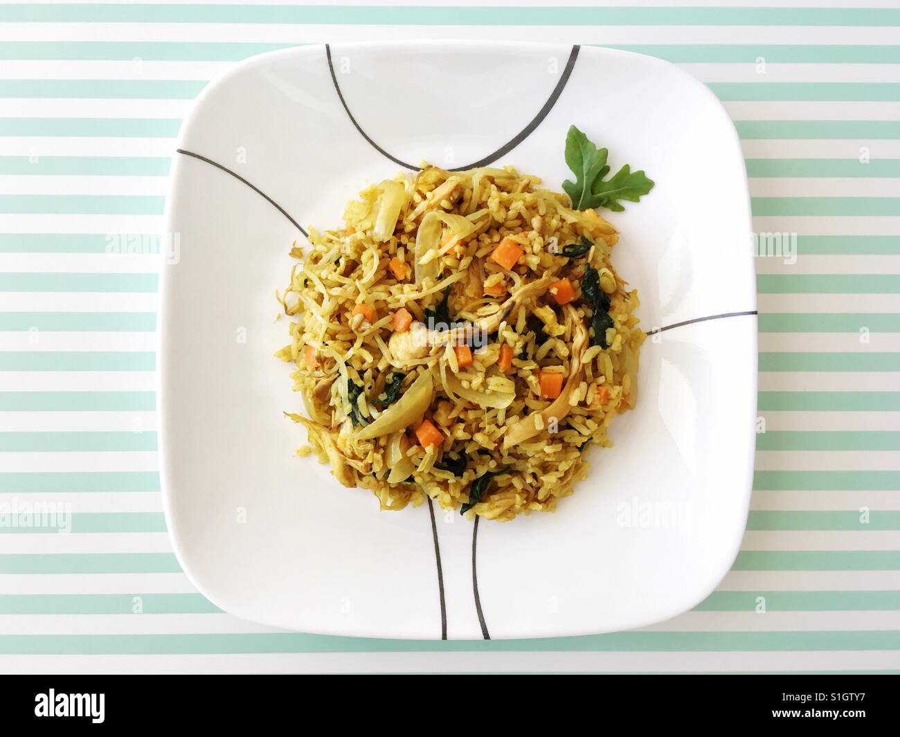 Curry fried rice on a plate against striped background Stock Photo - Alamy