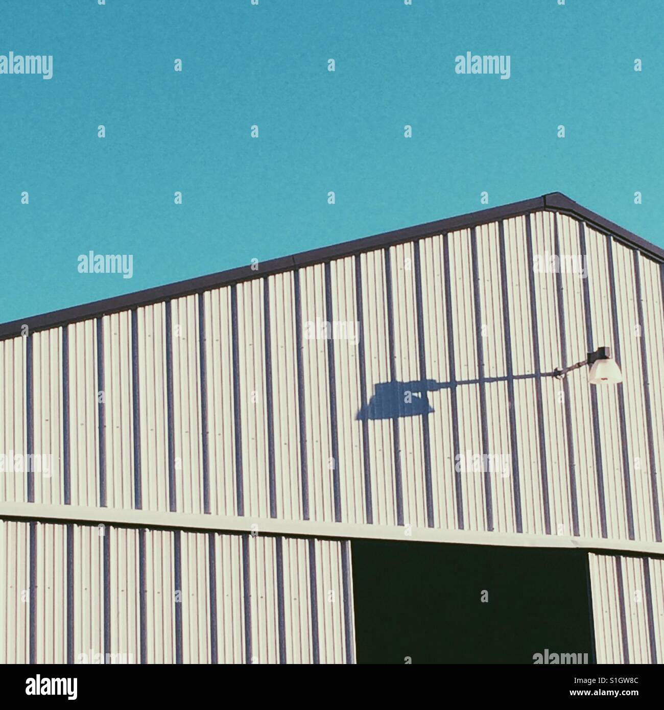 White metal shed or barn with modern light fixture contrasted against a ...