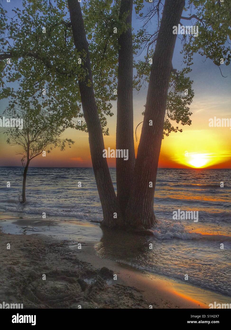 The sun setting on the horizon Stock Photo - Alamy