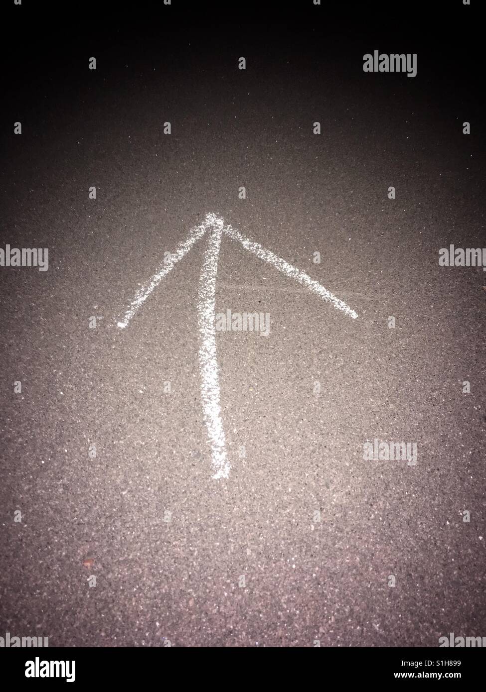 Arrow drawn on the road at night Stock Photo - Alamy