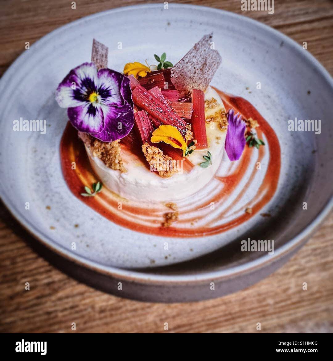 Cheesecake with rhubarb and edible flower decoration Stock Photo - Alamy