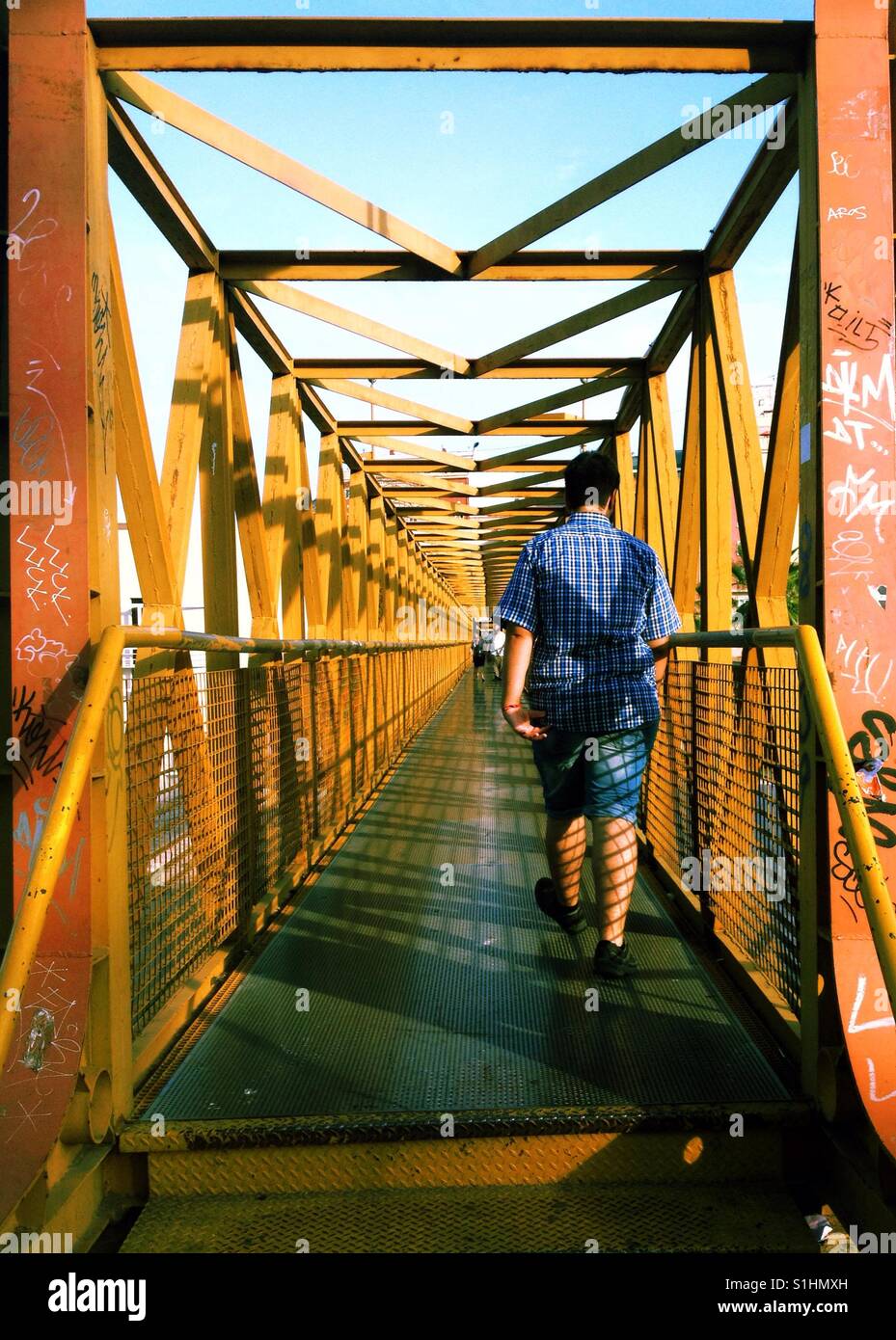 Man walking trough the colorful bridge Stock Photo - Alamy