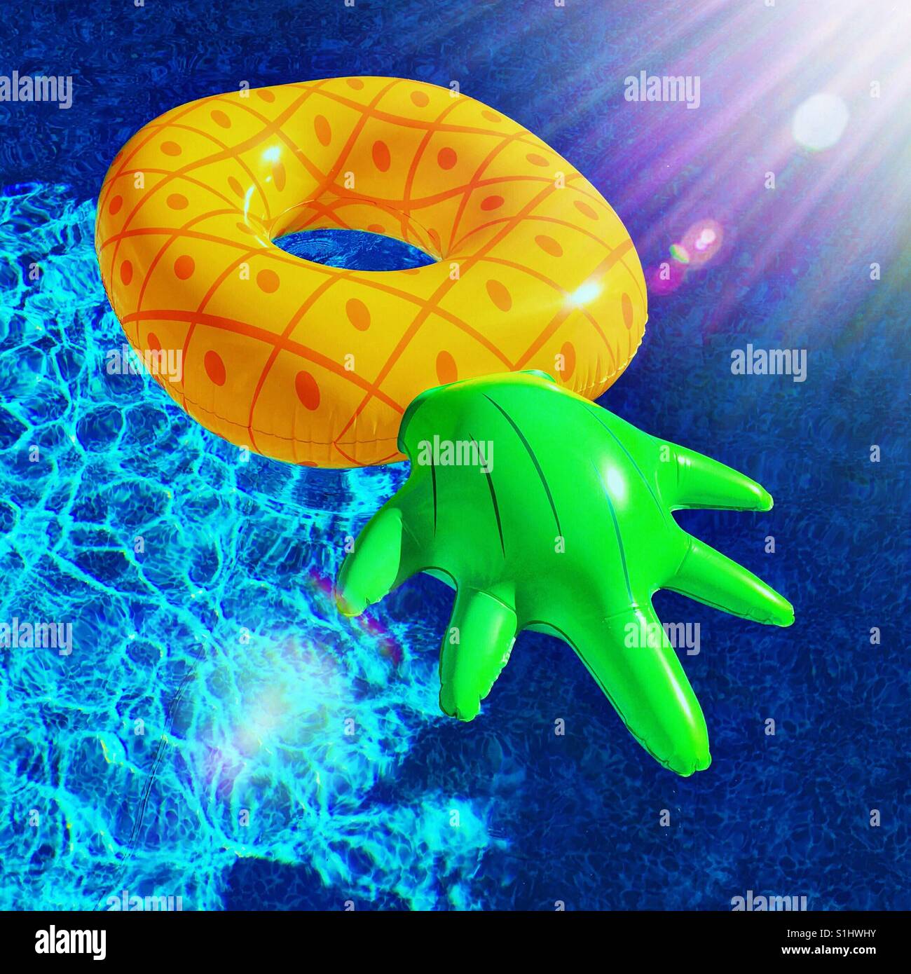 Inflatable pineapple floatie on clear blue waters on a sunny hot day ...