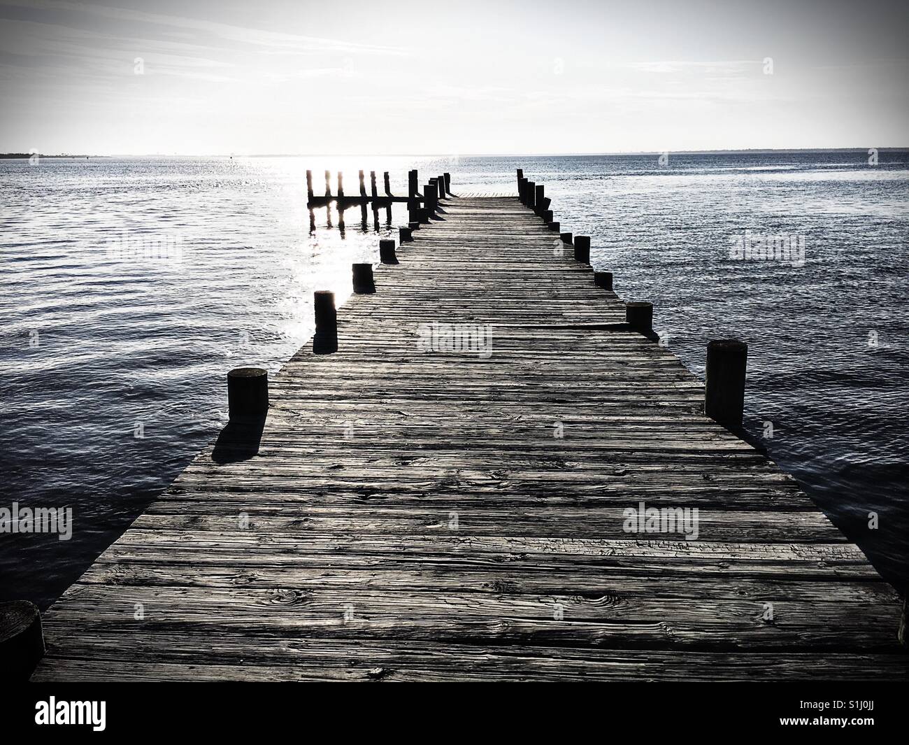 A weathered dock extends out into the water Stock Photo - Alamy