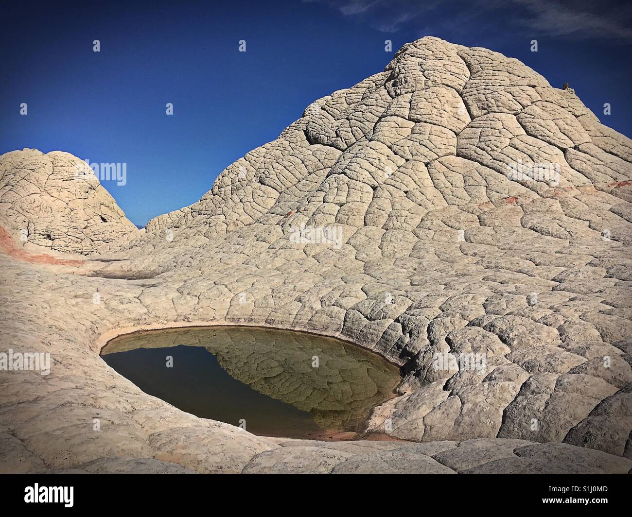 A small pond in front of a white cracked desert hillside Stock Photo ...