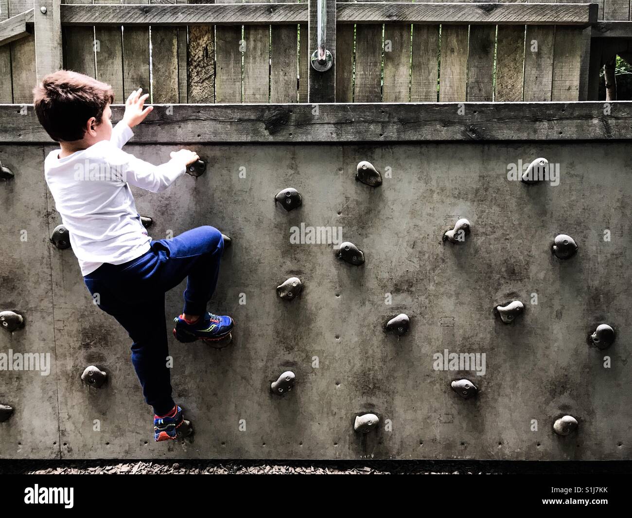 A young boy on a climbing wall attached to a wooden fort Stock Photo ...