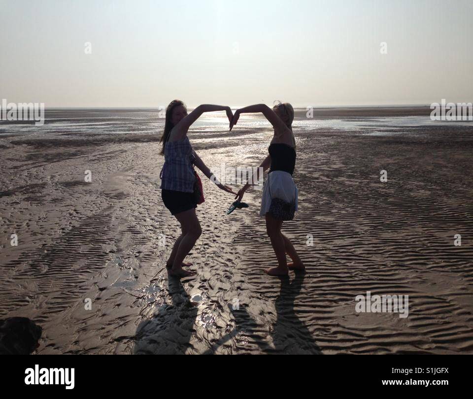 Two girls make a love heart with the arms Stock Photo - Alamy