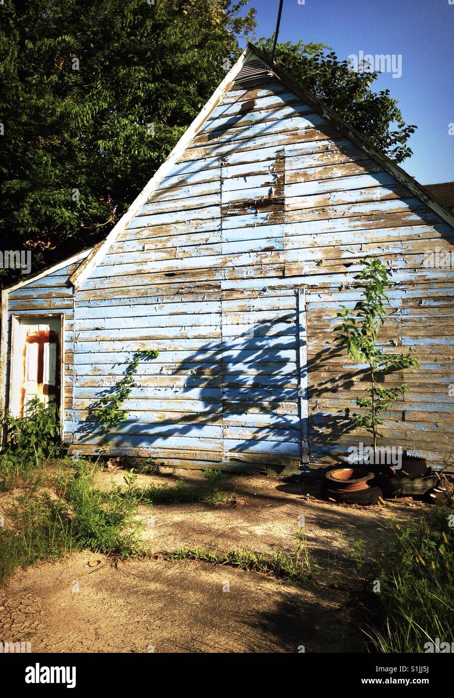 Sunlit side of worn blue building Stock Photo - Alamy
