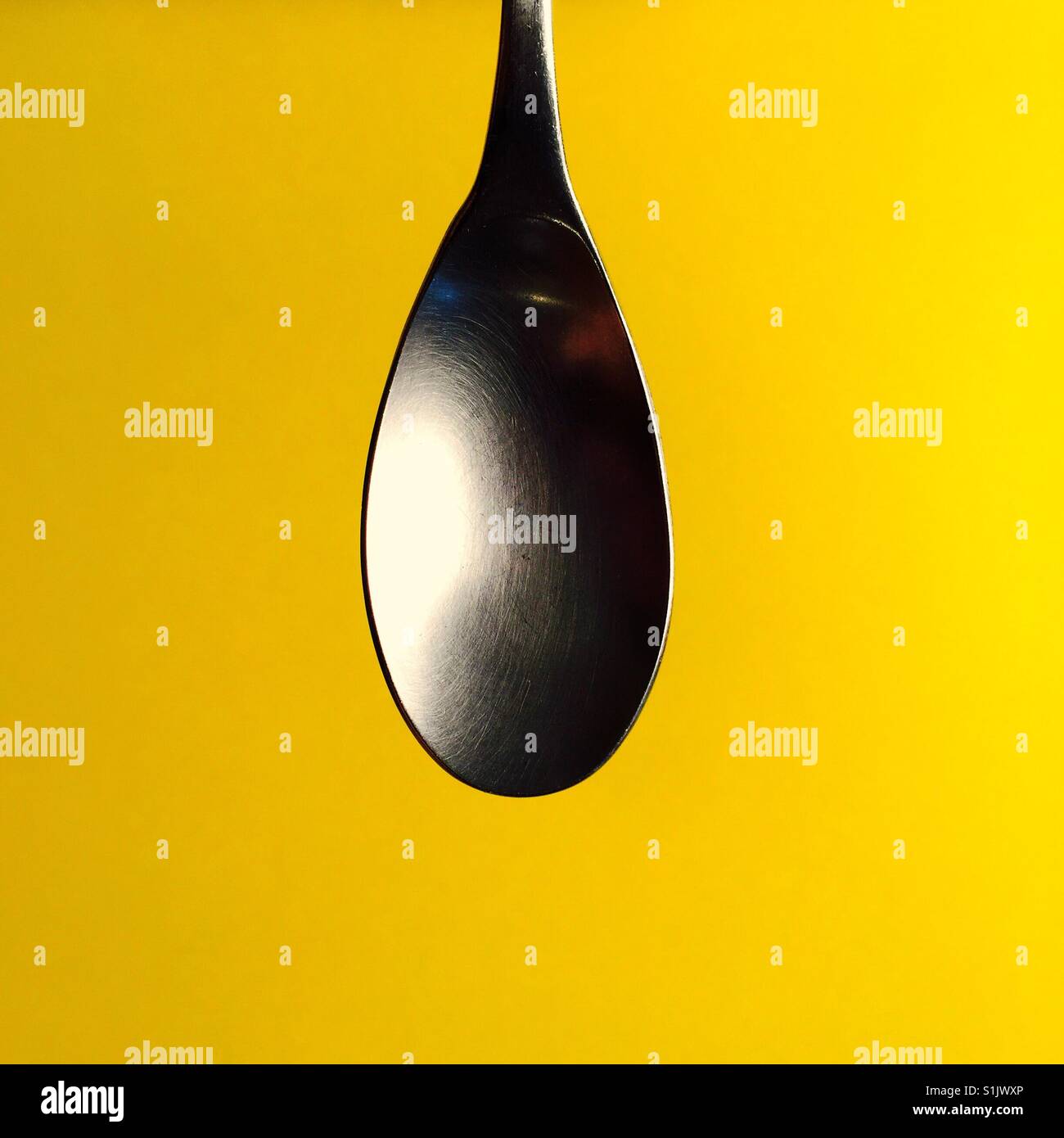 A close up overhead shot of a single empty spoon above a yellow ...