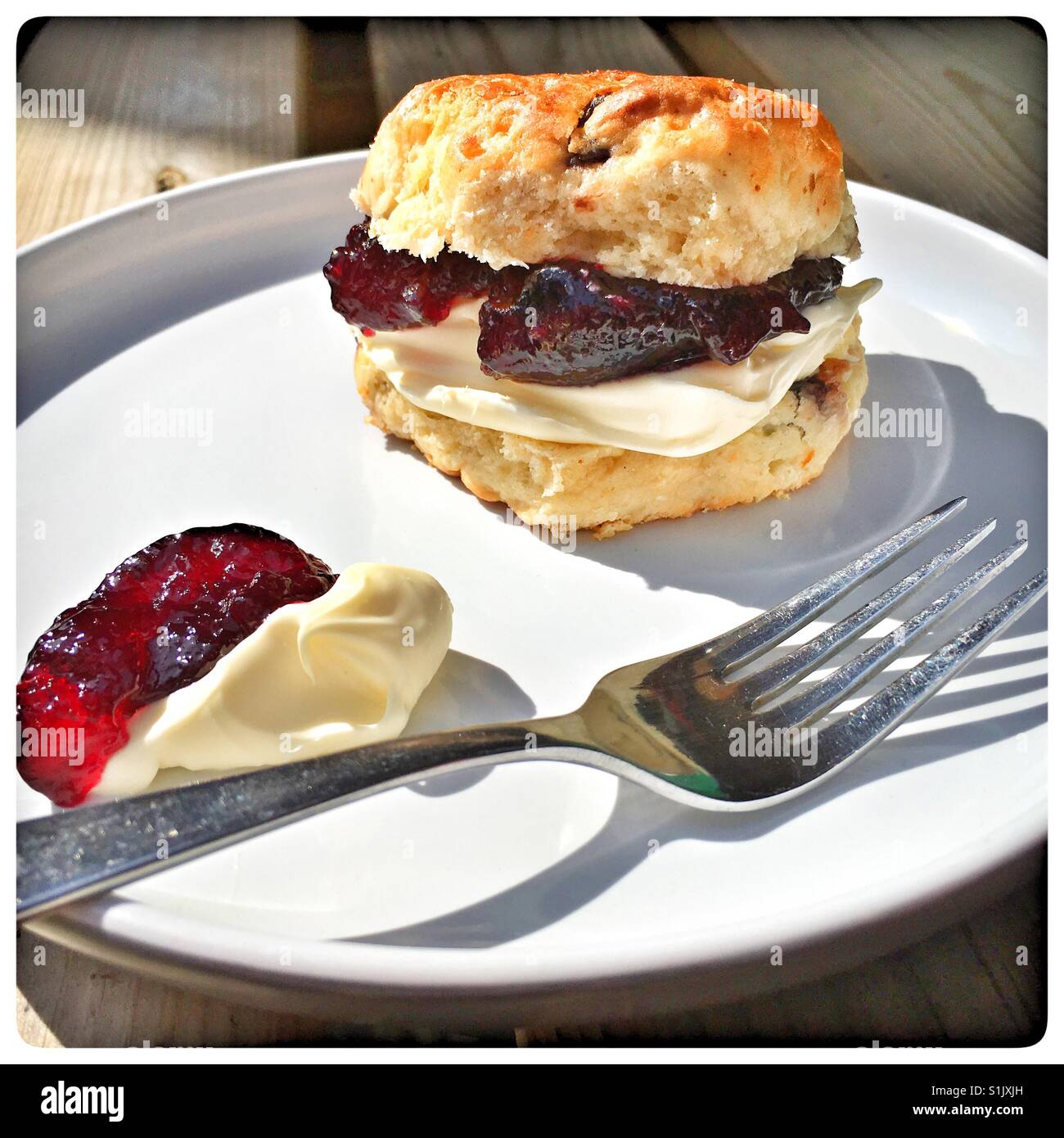 Traditional British Cream Tea. A fruit scone filled with butter ... Traditional British Cream Tea. A fruit scone filled with butter ...