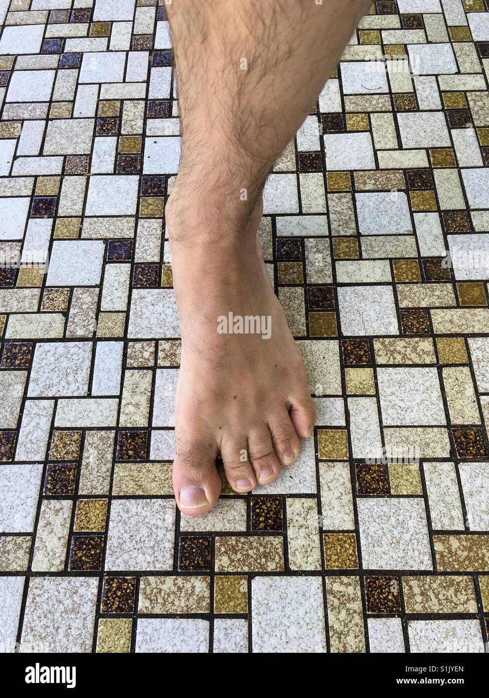 Man's foot on tiled floor Stock Photo - Alamy
