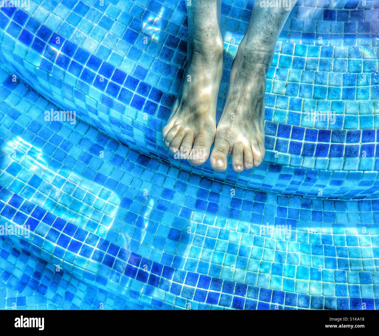 Keeping cool. Feet in a swimming pool Stock Photo - Alamy