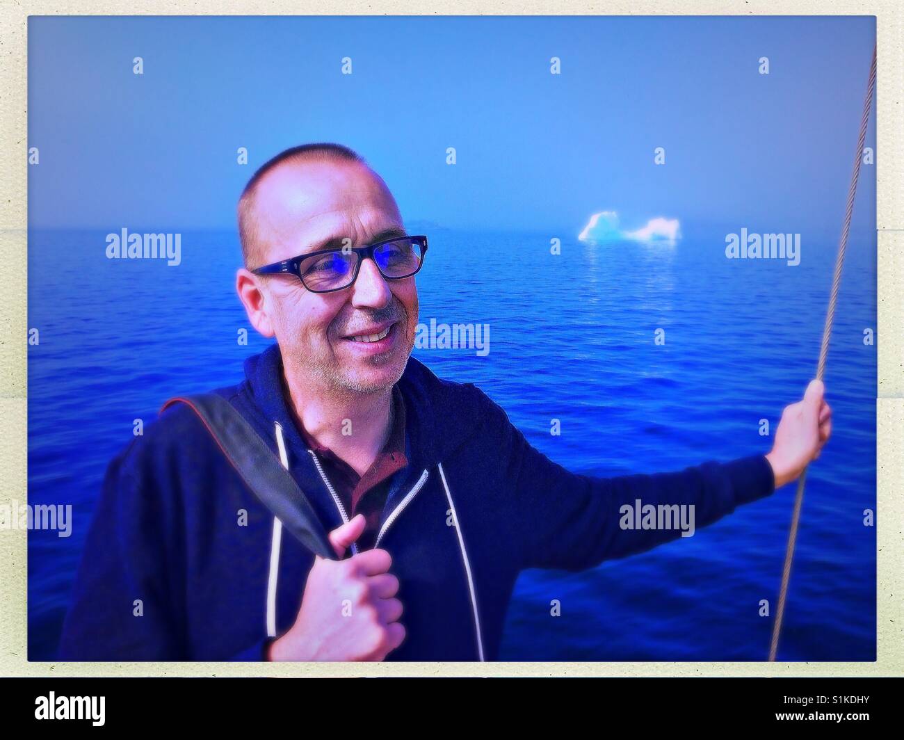 Smiling middle aged man and iceberg in summer, Northern Peninsula ...