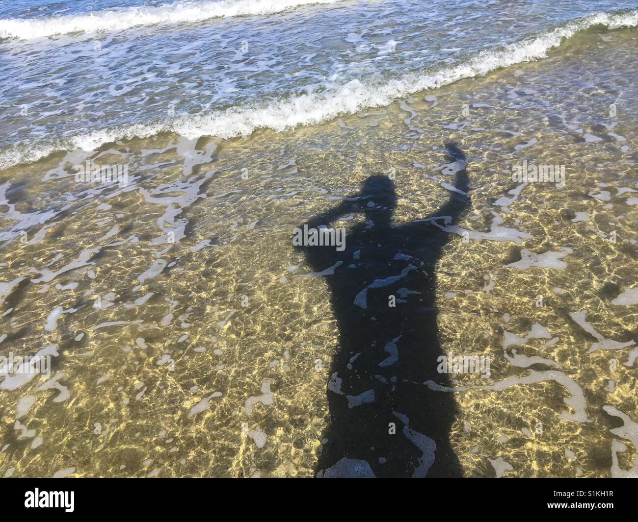 Shadow of a man waving at the beach Stock Photo - Alamy